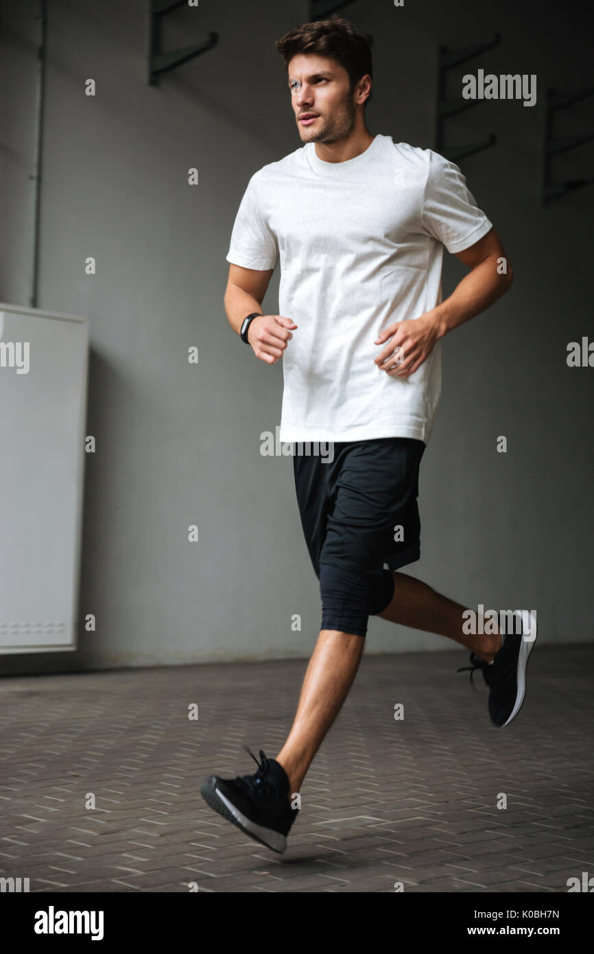 Image of handsome young sports man running at the stadium outdoors ...