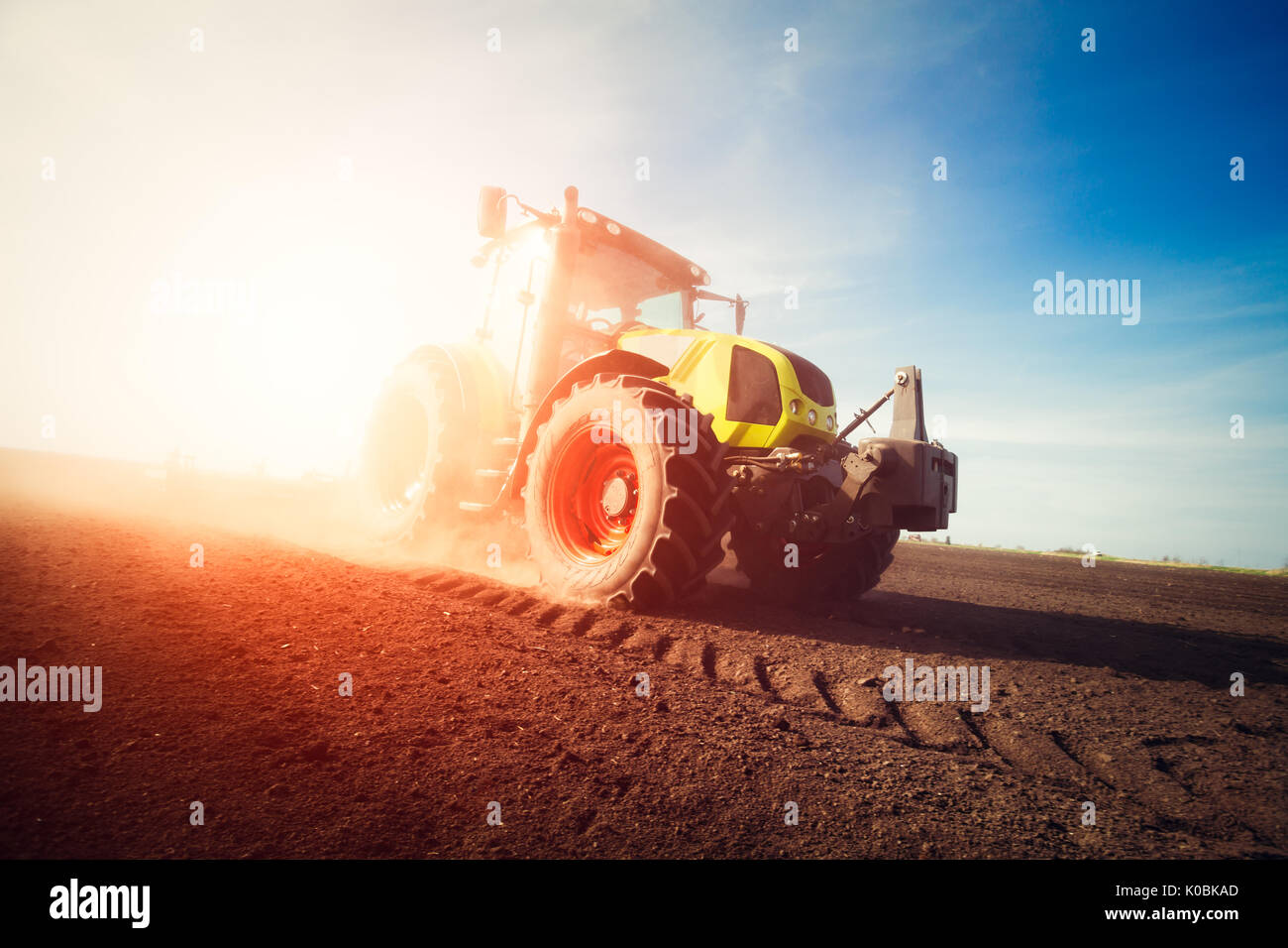 Tractor working on farm land on sunset Stock Photo - Alamy
