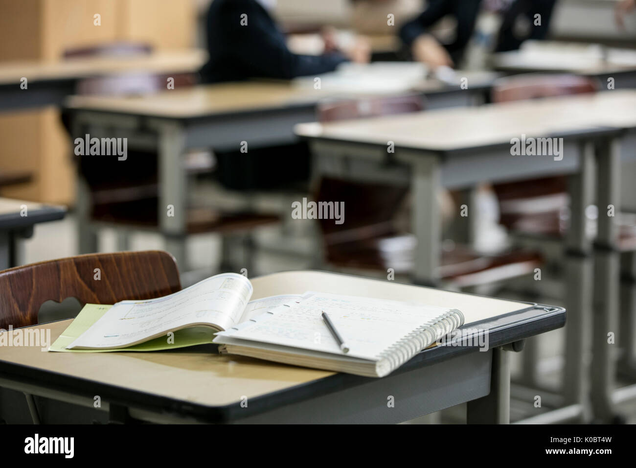Notebooks and pencil on desk in classroom Stock Photo - Alamy