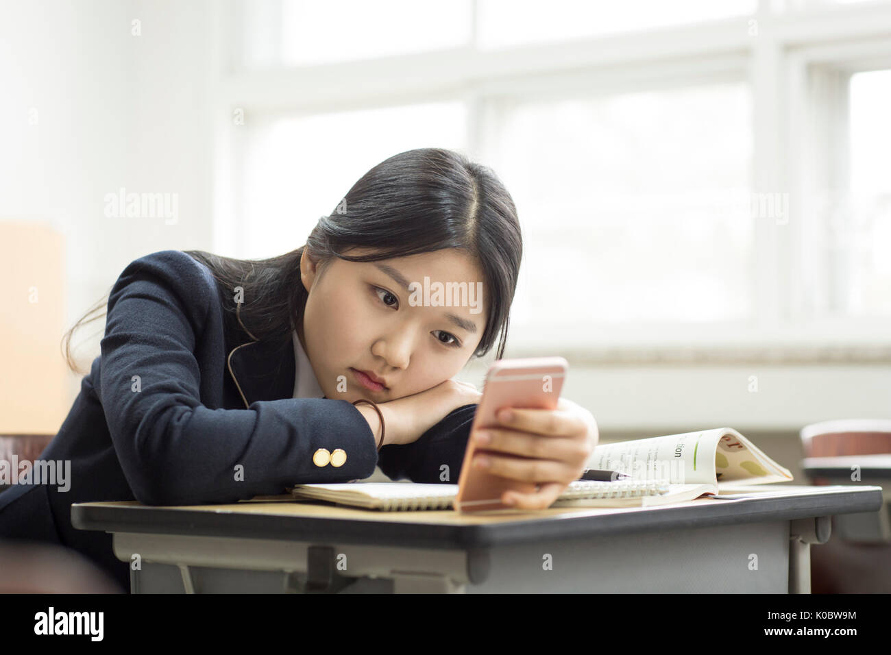 Portrait of school girl gloomy using smartphone in classroom Stock ...