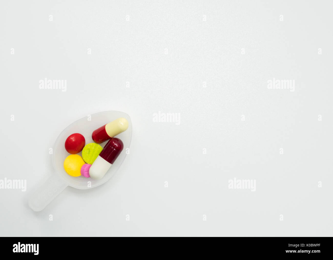 Colorful pills in teaspoon on white background Stock Photo - Alamy