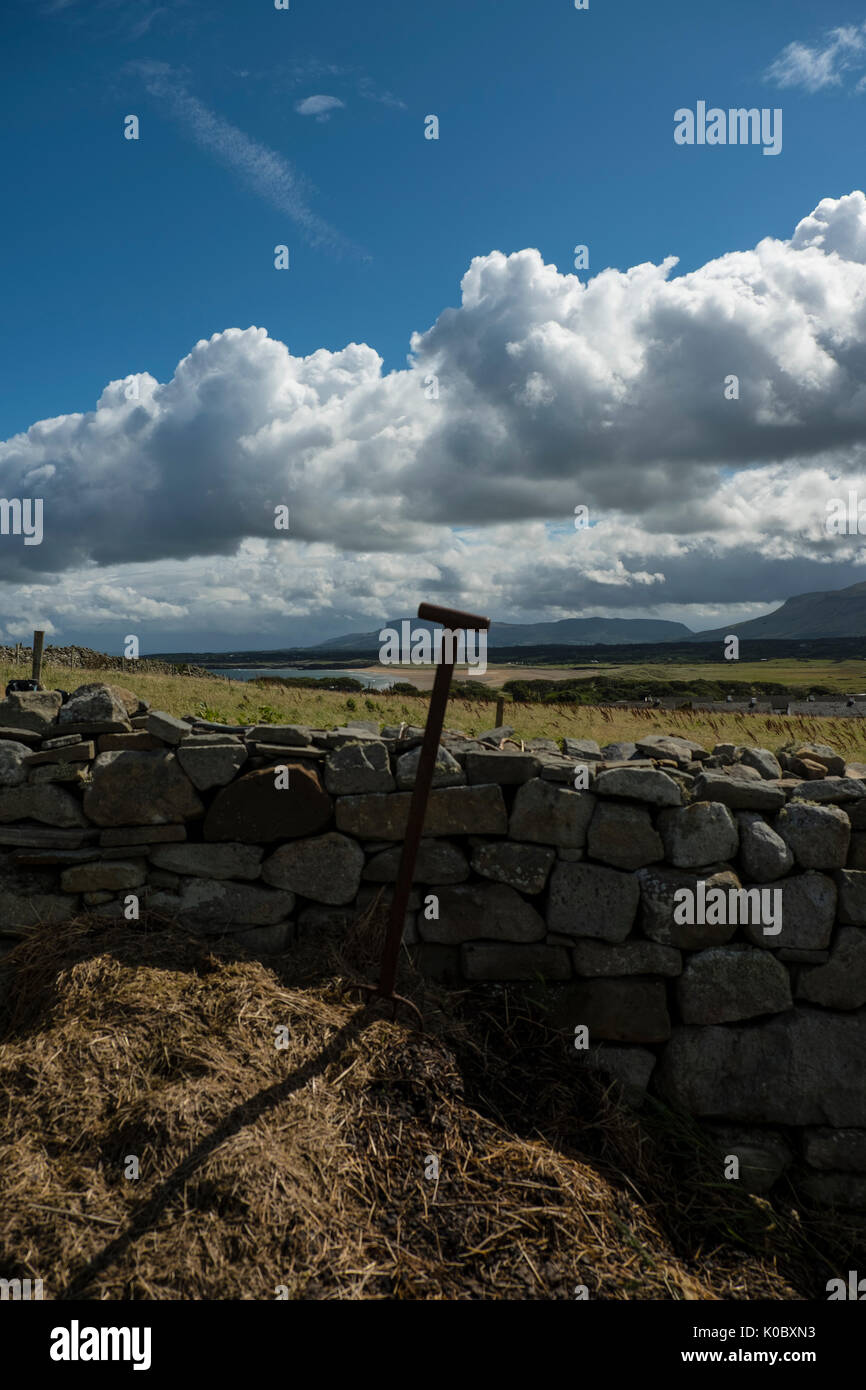 Spade resting on dry stone wall with beautiful landscape in background ...