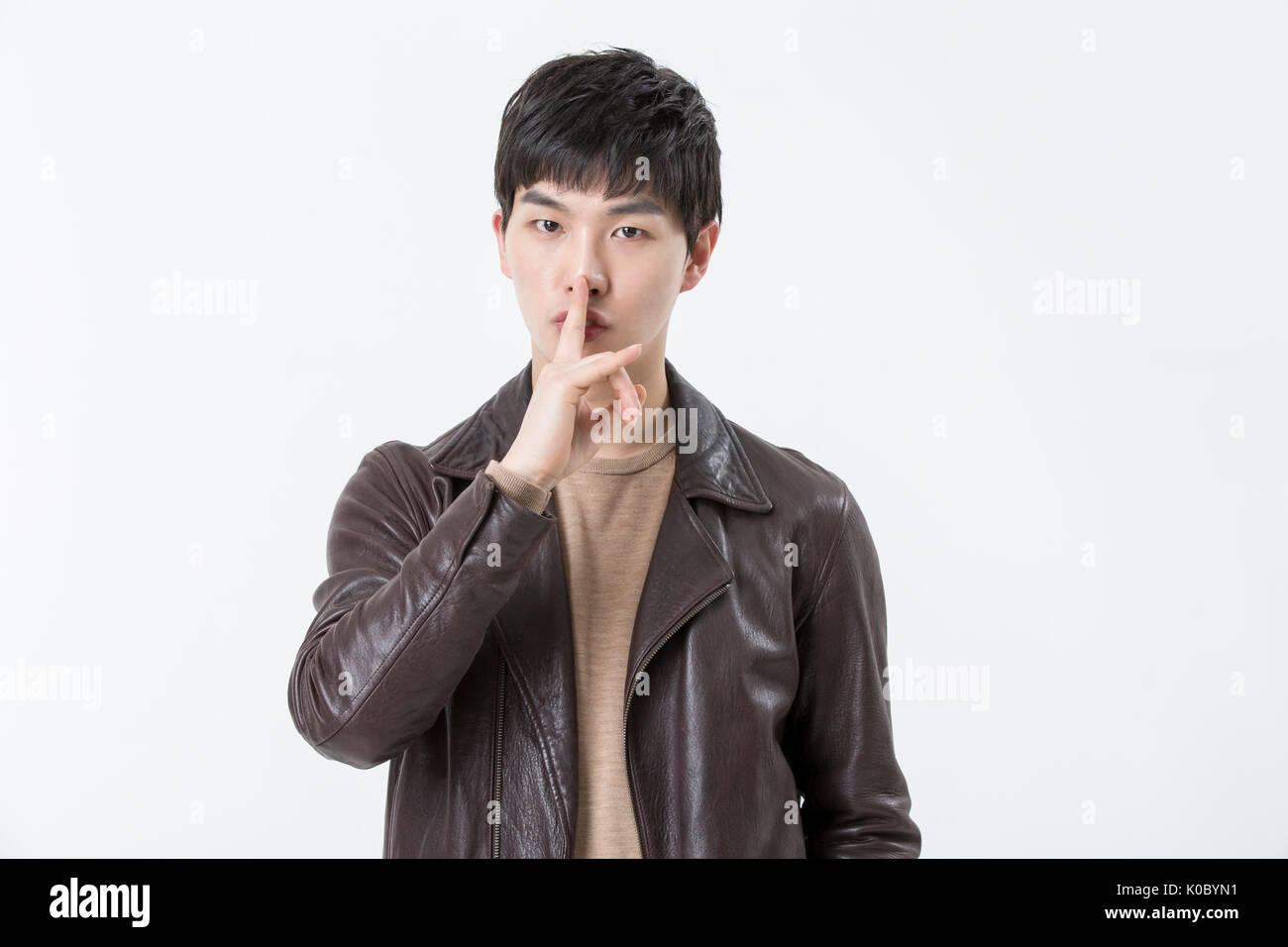 Portrait of young man with hush sign Stock Photo - Alamy