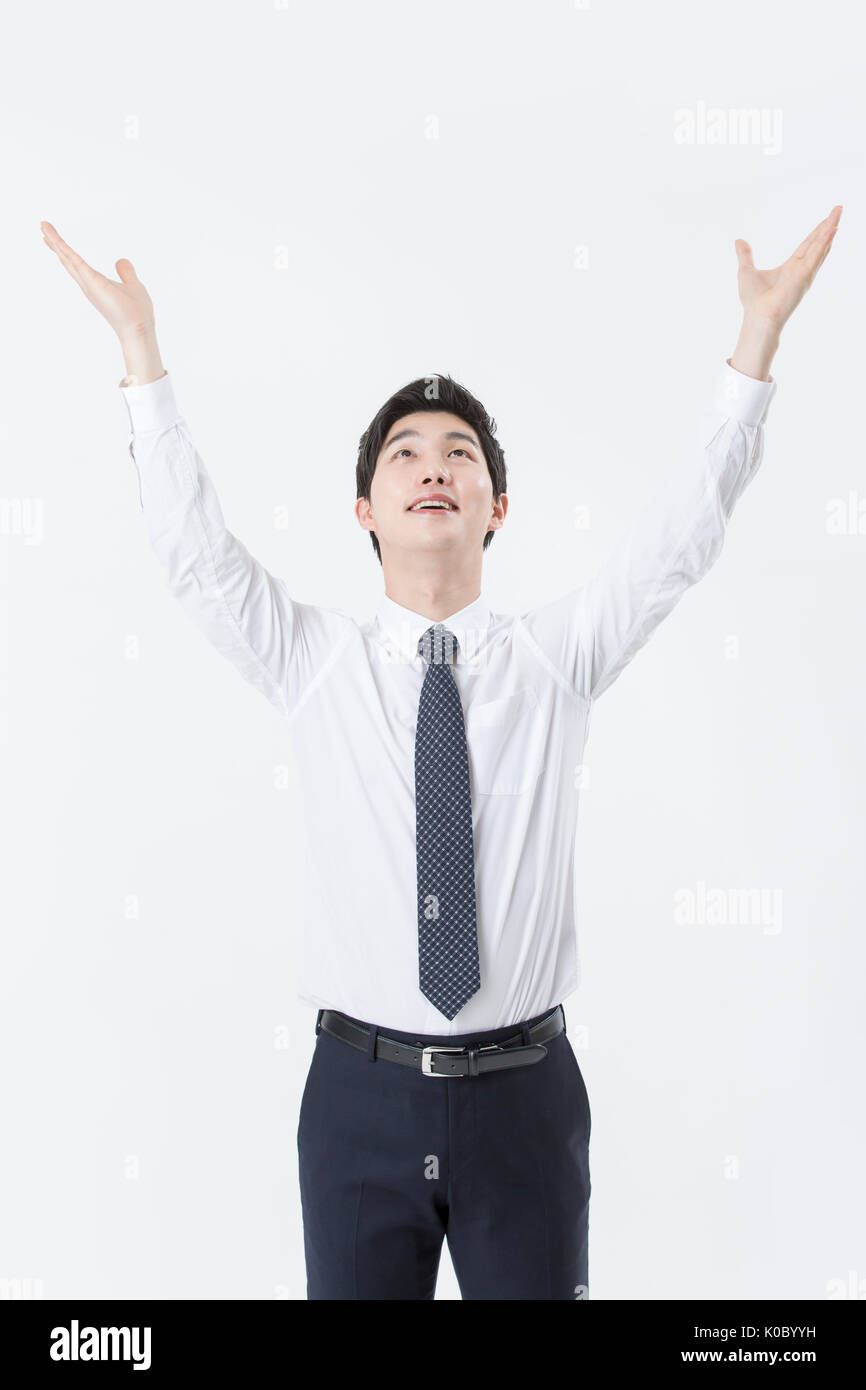 Young smiling businessman raising hands looking up Stock Photo - Alamy