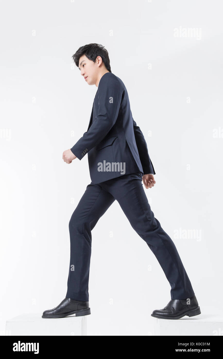 Side view of young businessman in suit walking Stock Photo - Alamy