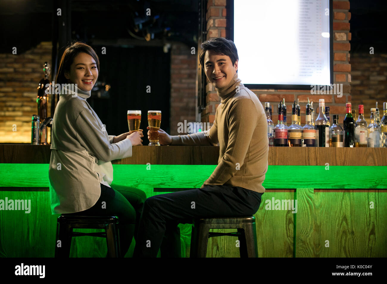 Two smiling coworkers drinking beer at bar Stock Photo - Alamy