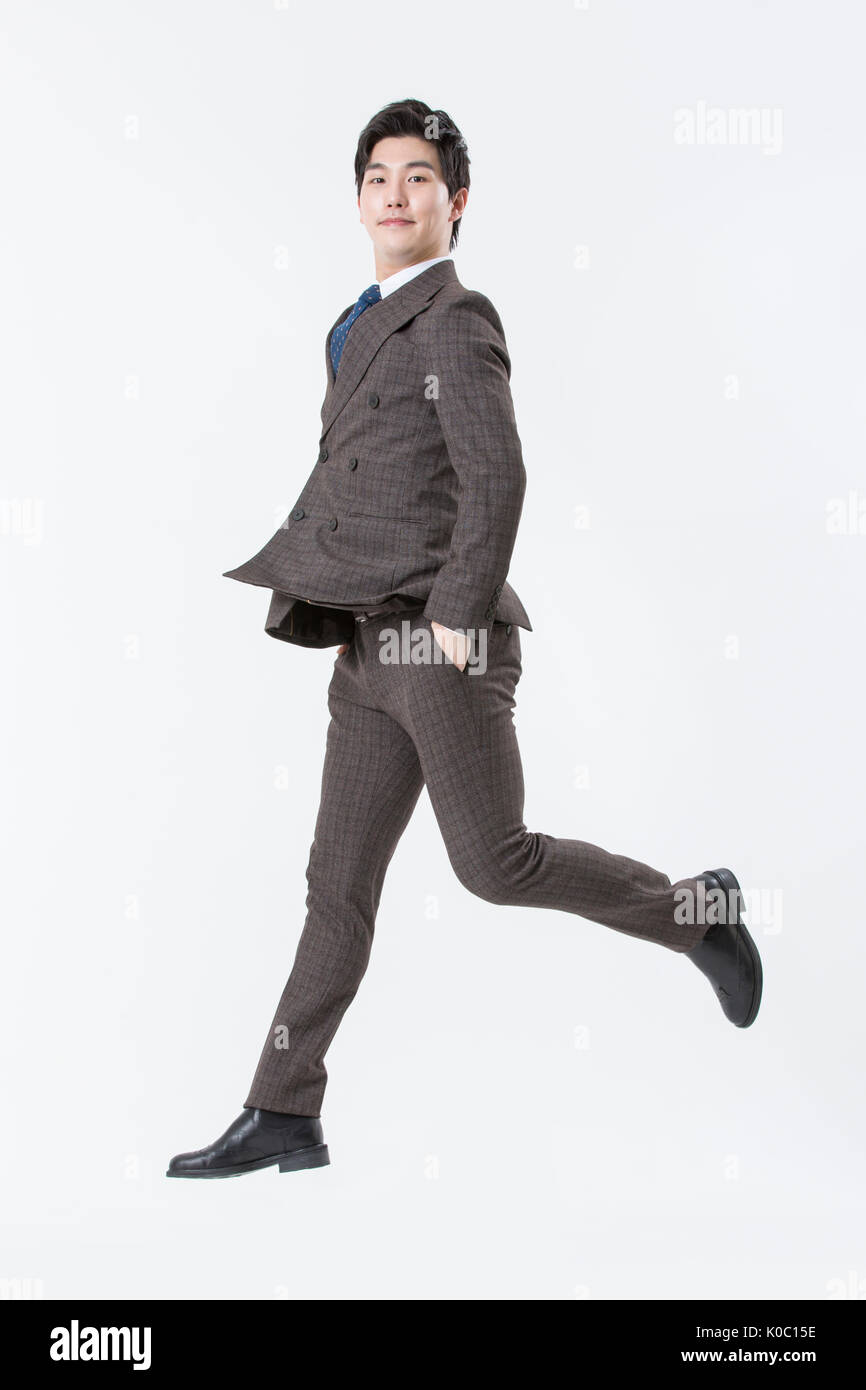Side view of young man in suit jumping Stock Photo - Alamy