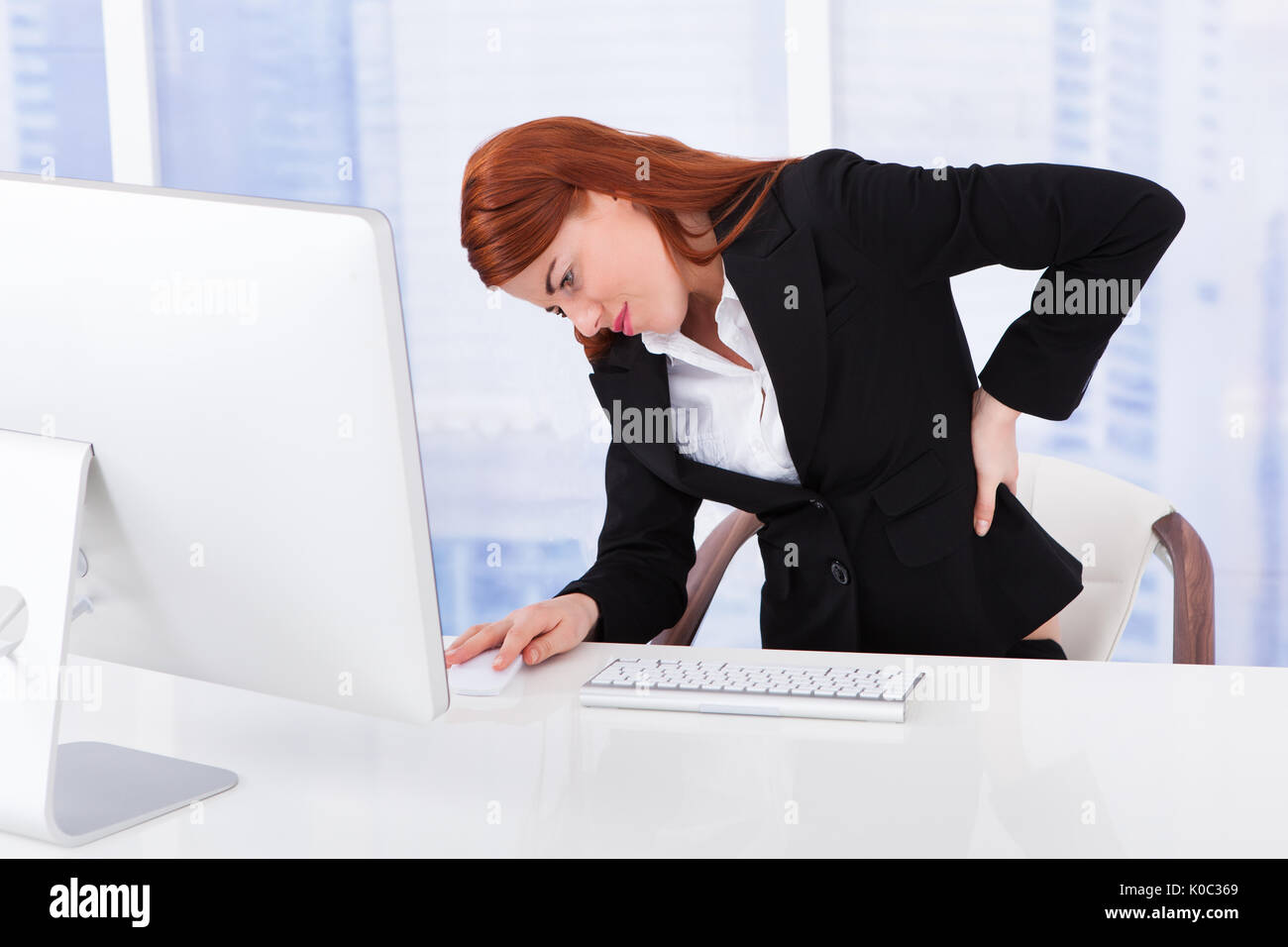 Tired young businesswoman suffering from backache while working at ... Tired young businesswoman suffering from backache while working at ...