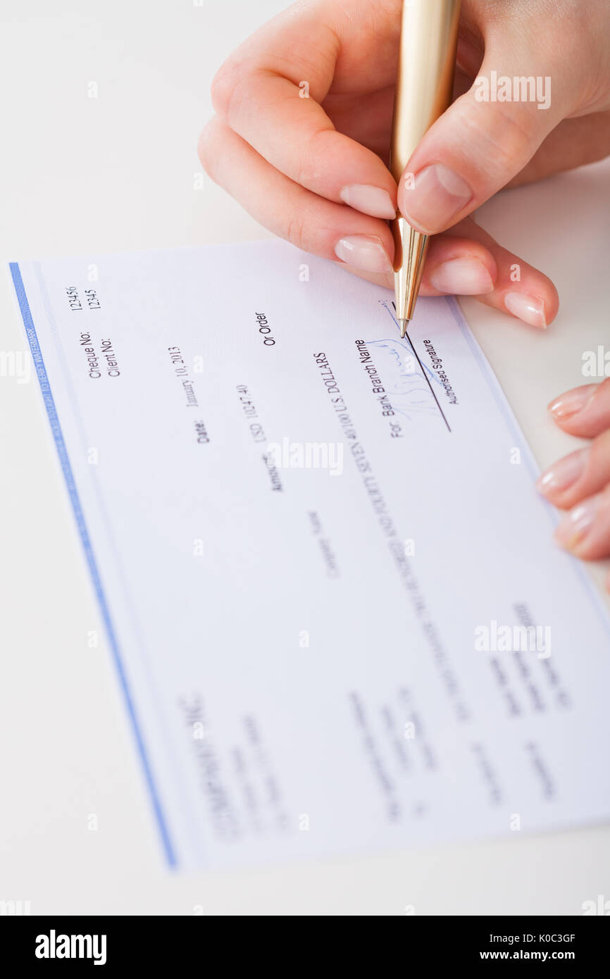 Cropped image of businesswoman signing cheque at desk Stock Photo - Alamy