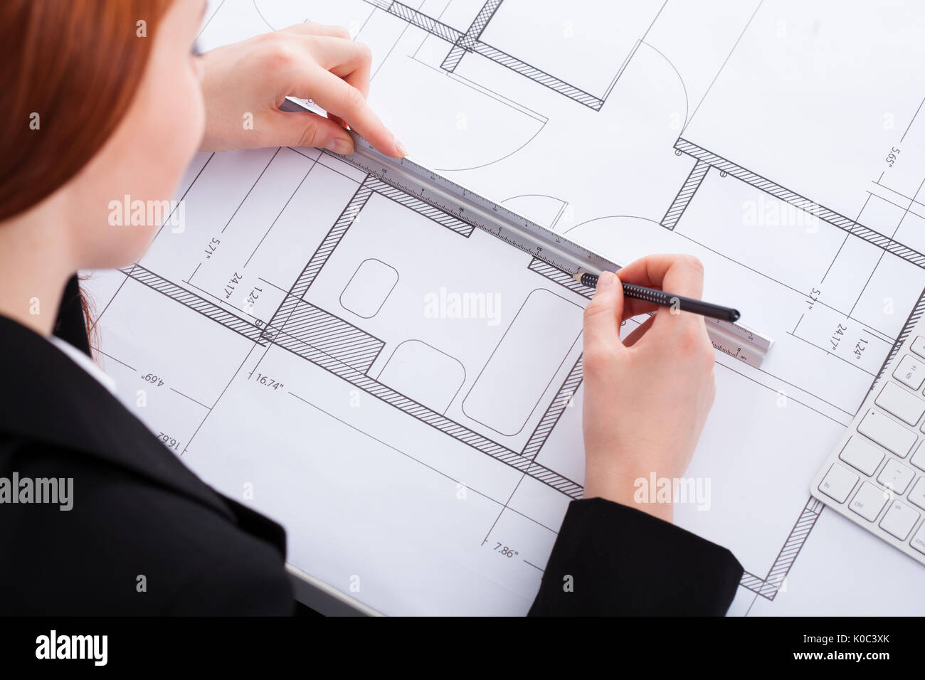 High angle portrait of businesswoman working on blueprint in office ...