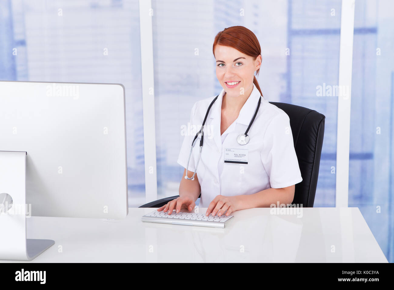 Portrait of confident young female doctor using computer in hospital ...