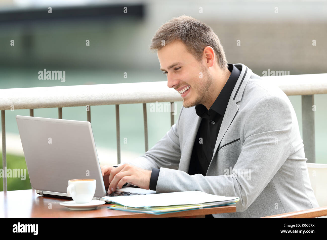 Happy executive man typing in a laptop sitting in a coffee shop Stock ...