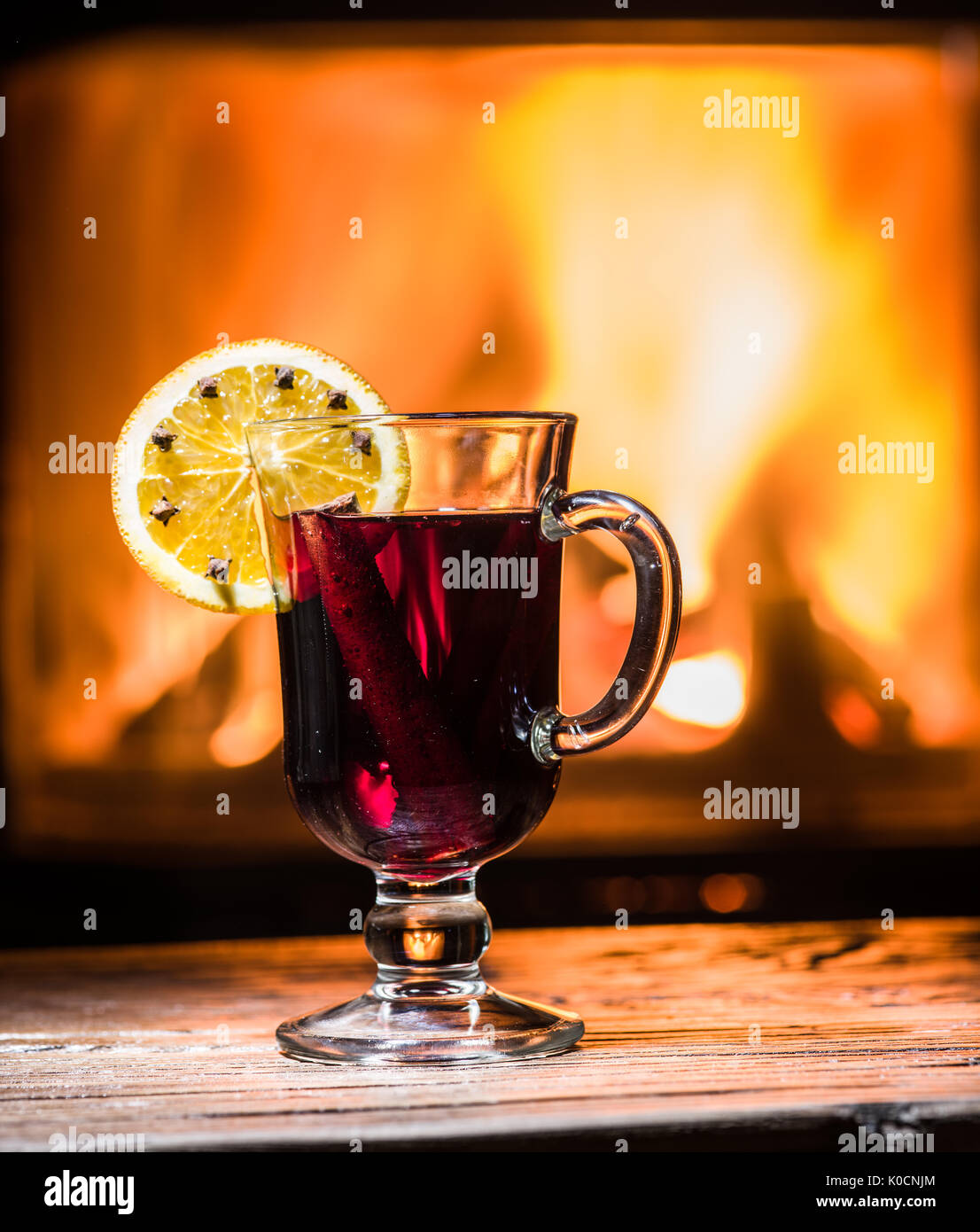 Hot mulled wine with orange slice, cloves and cinnamon stick. Fireplace ...