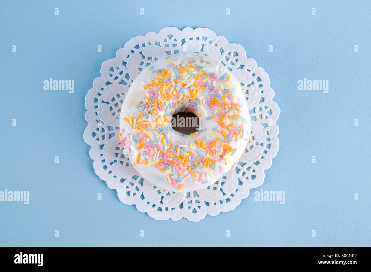 a multicolor donuts presented on a doily paper and a pop colorful ...