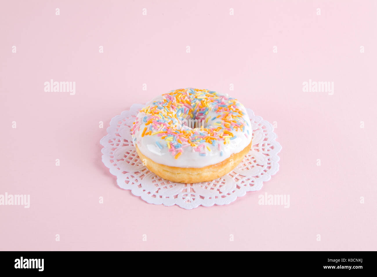 a multicolor donuts presented on a doily paper and a pop colorful ...
