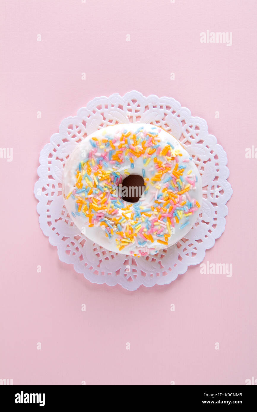 a multicolor donuts presented on a doily paper and a pop colorful ...