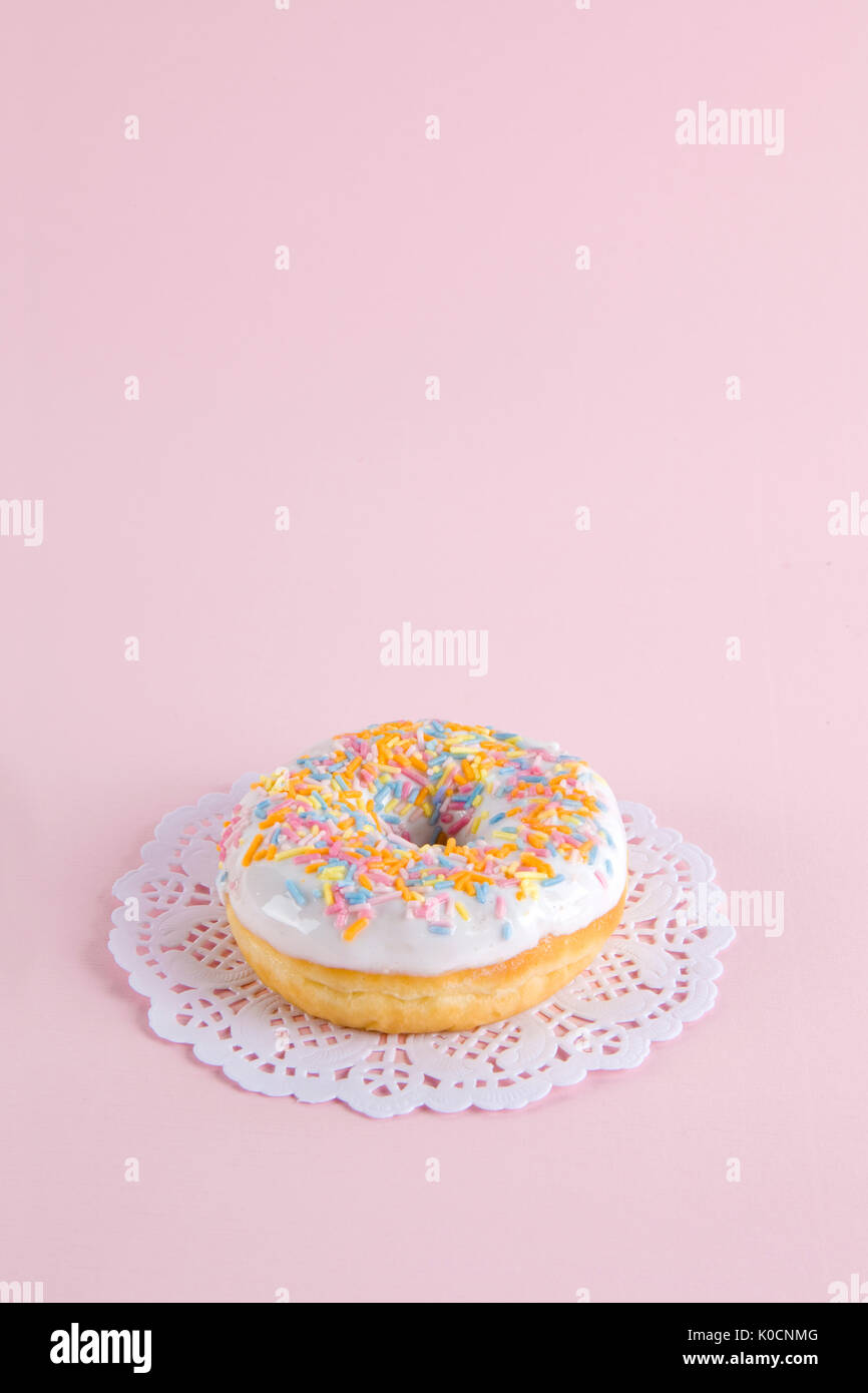 a multicolor donuts presented on a doily paper and a pop colorful ...