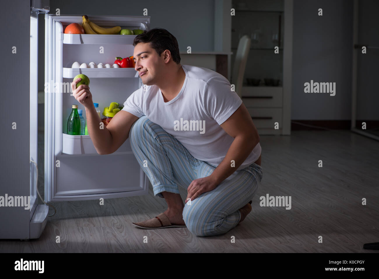 Man at the fridge eating at night Stock Photo - Alamy