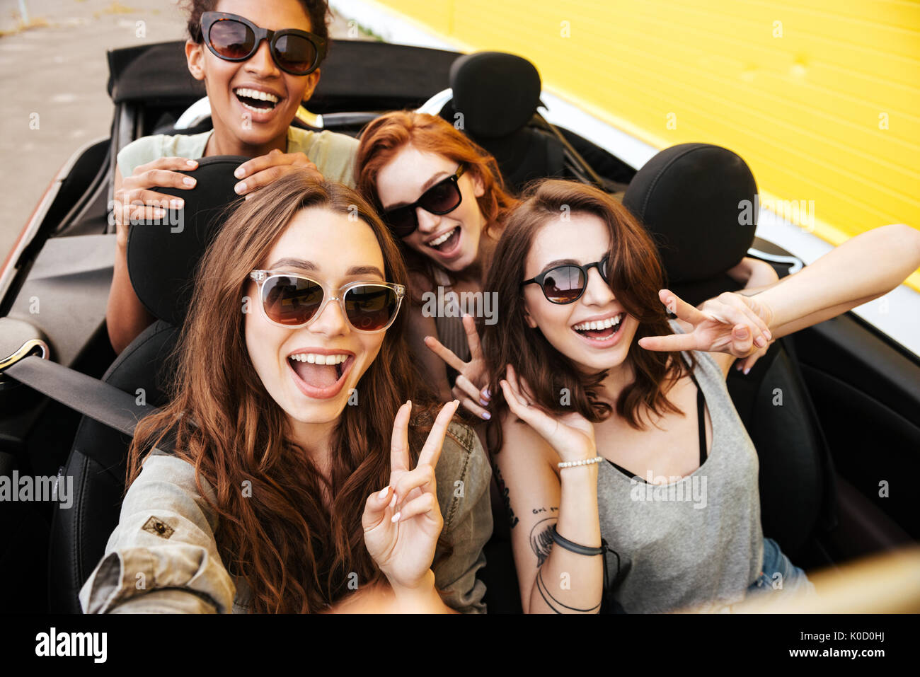 Picture of smiling emotional four young women friends sitting in car ...