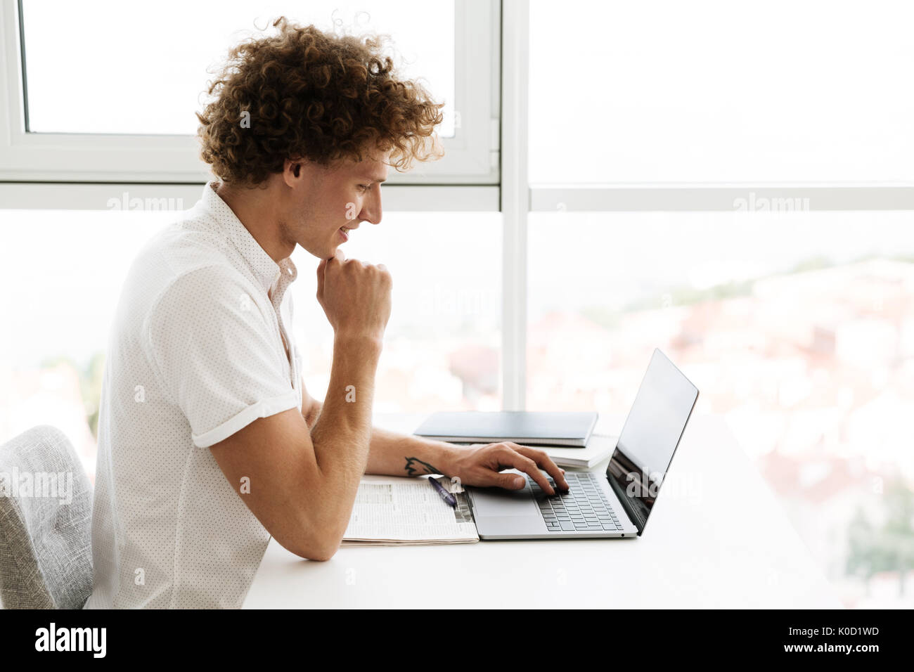 Picture of handsome concentrated serious man sitting at the table near ...