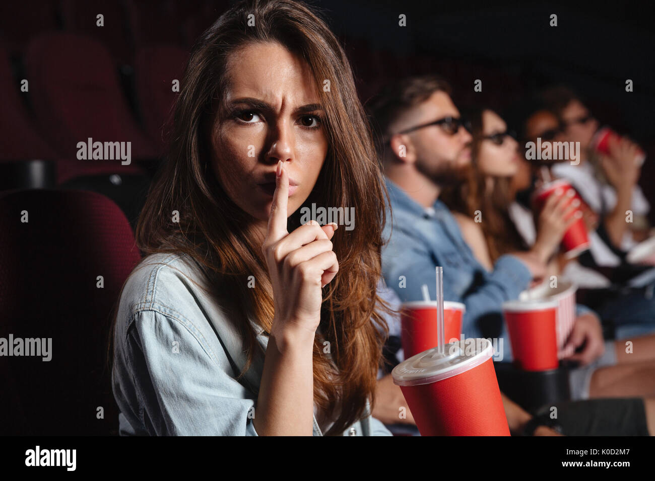 Picture of young lady sitting in cinema watch film and showing silence ...