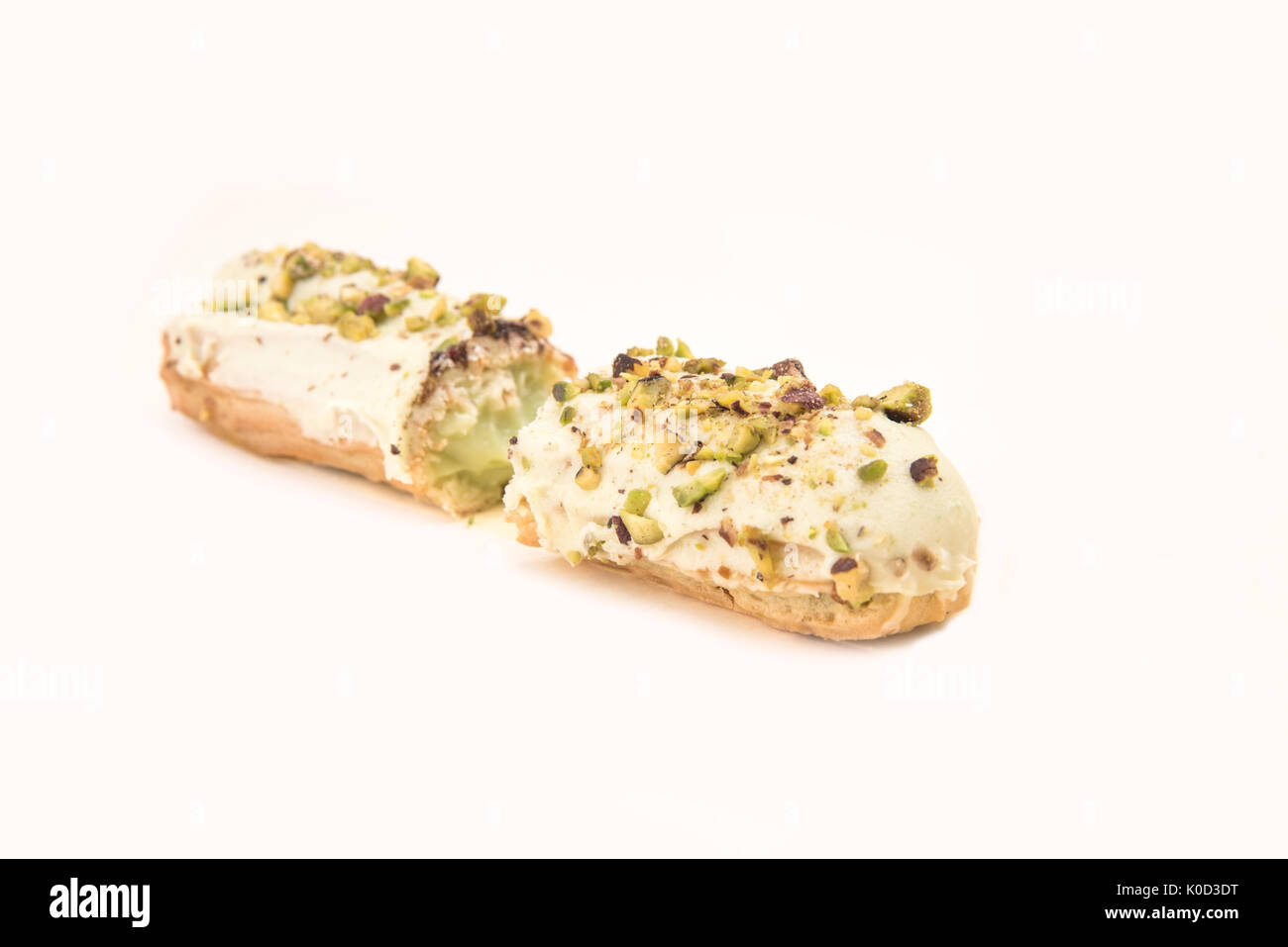 Close up of cut eclair with white cream and nuts isolated over white ...