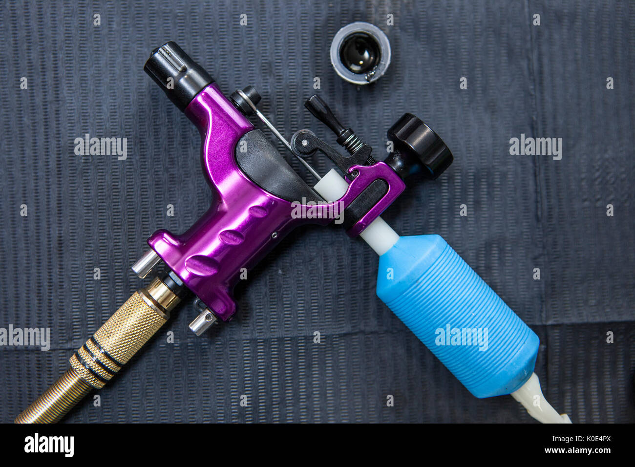 Tattoo artist table with ink small cup and purple gun ink machine ...