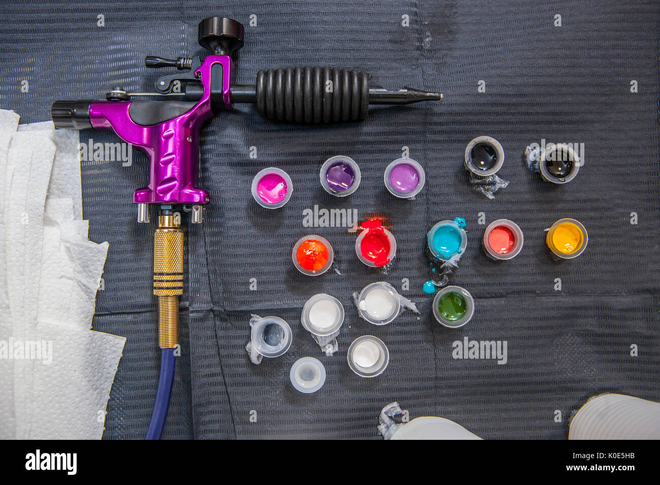 Tattoo artist table with several small cups and gun ink machine ...