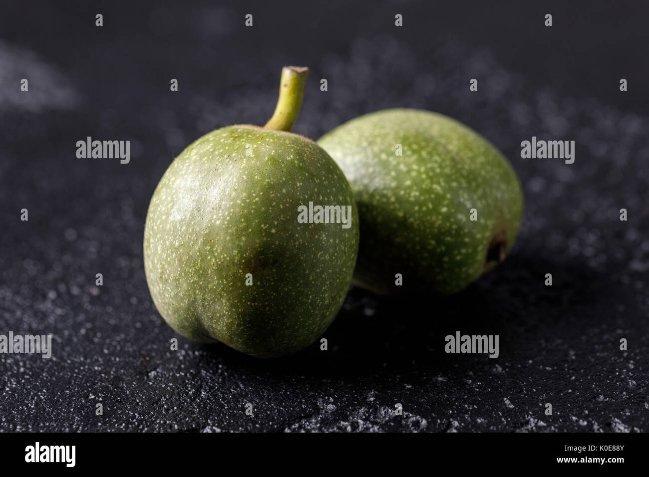 Fresh green walnuts in the skin just from the tree. Walnuts on a black ...
