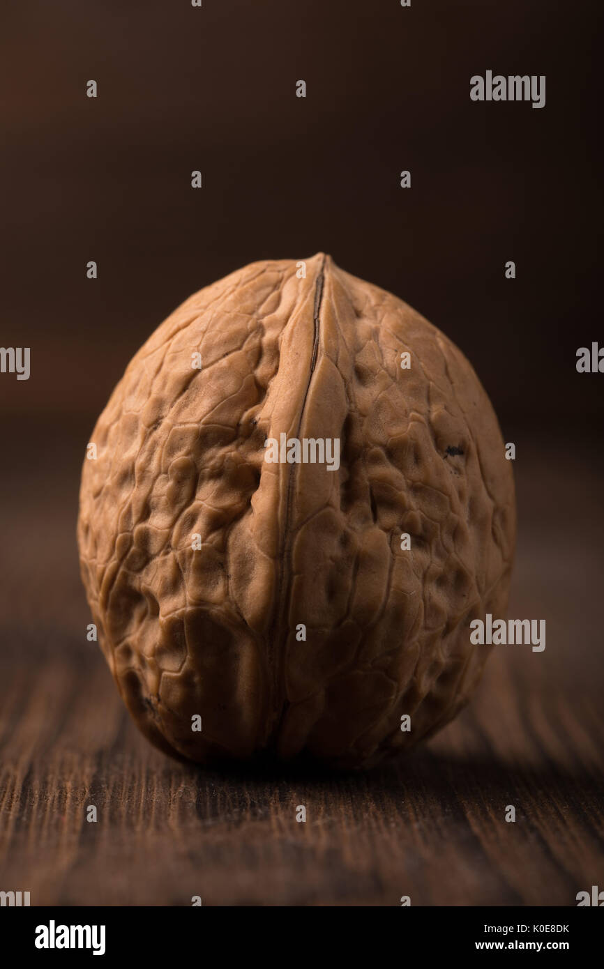 A beautiful large walnut in a shell on a wooden background. Nut and ...