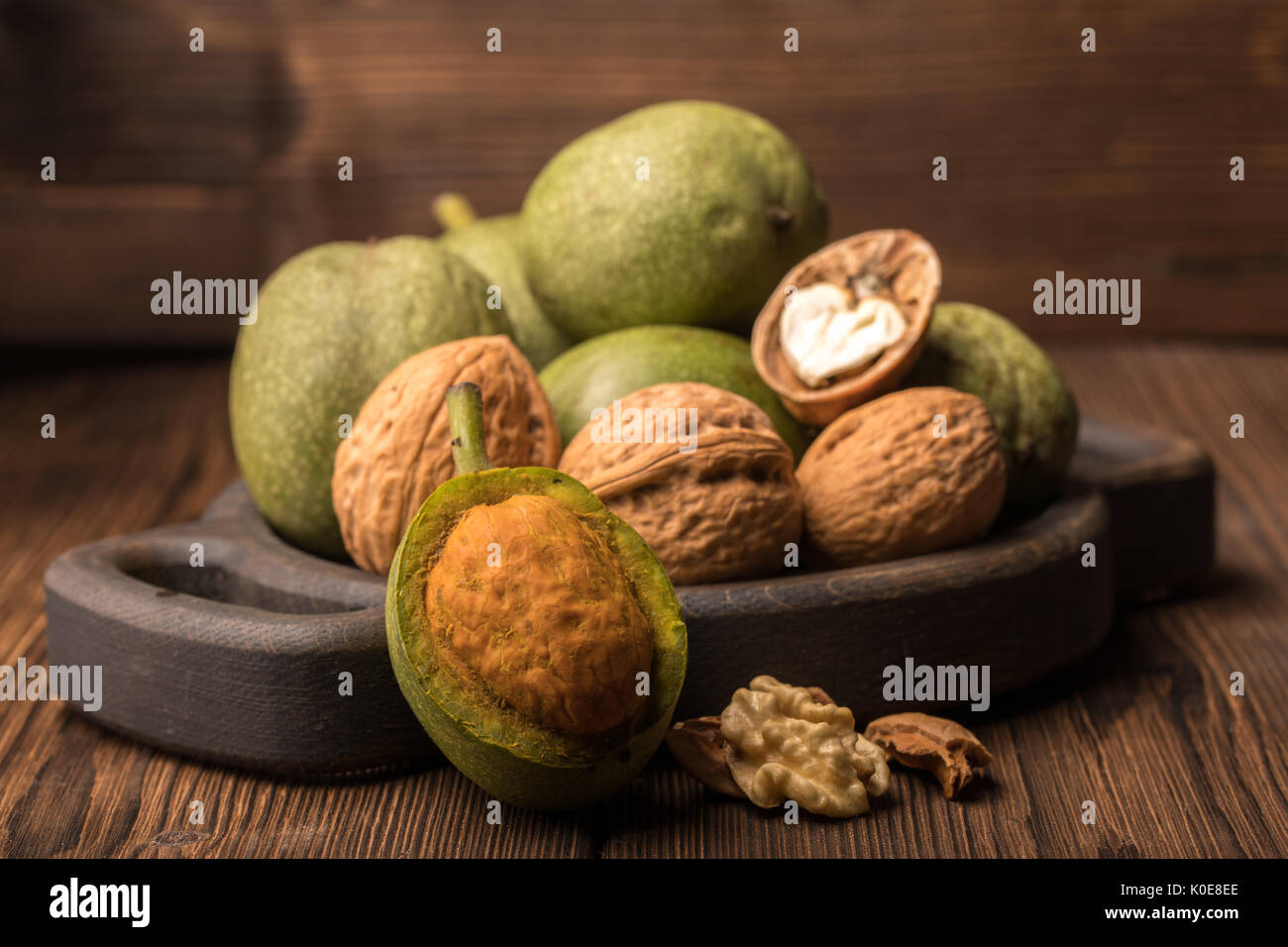 Fresh harvest of walnuts on a wooden background. Green and brown nuts ...