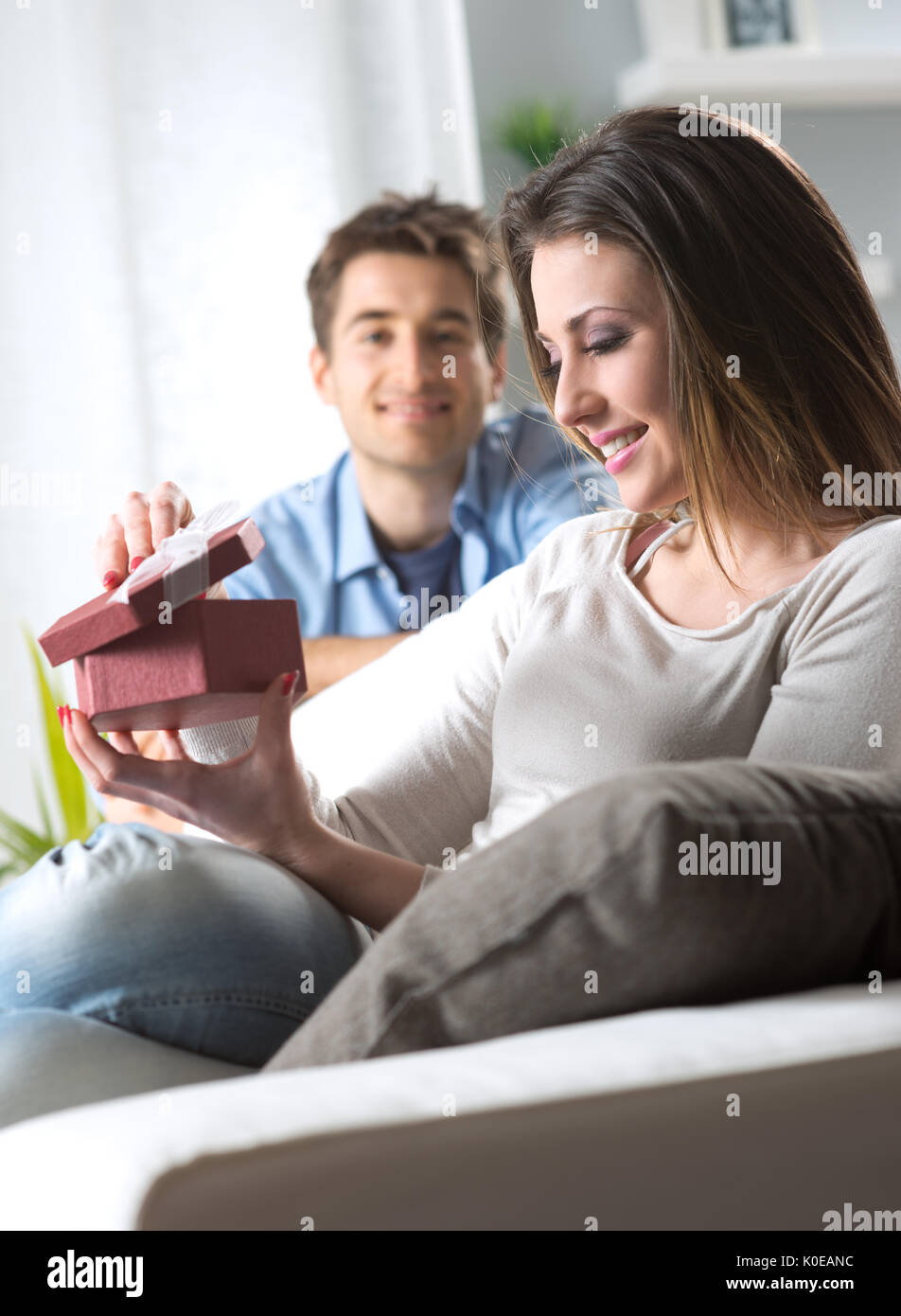 Young woman receiving a surprise gift box from her boyfriend at home ...