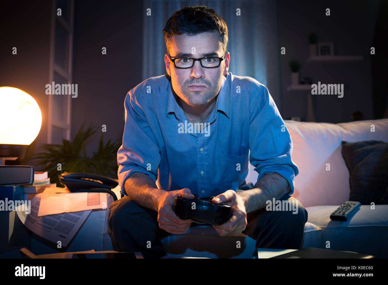 Man playing videogames late at night in a messy living room, sitting on ...