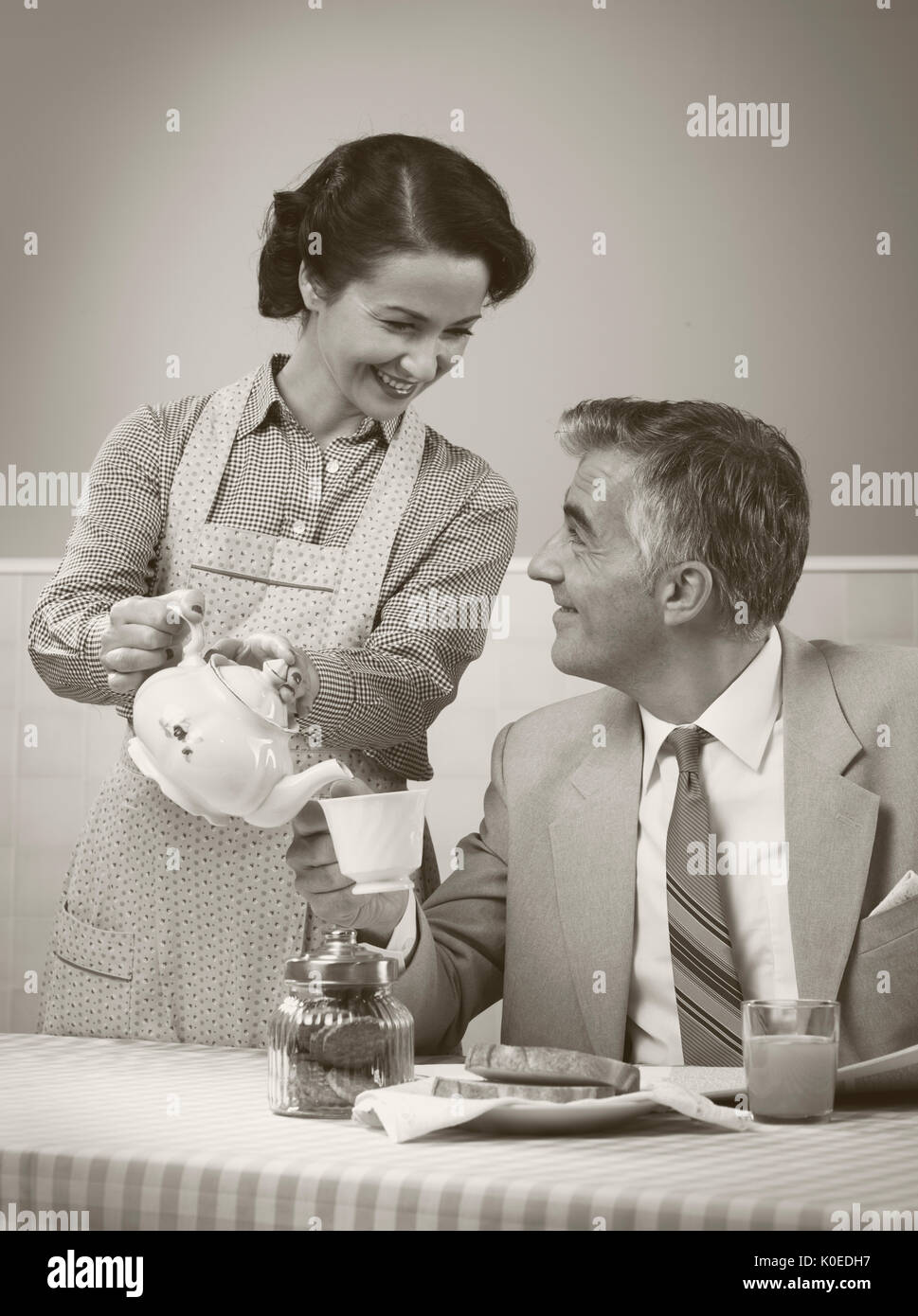 1950s beautiful woman serving tea for breakfast to her smiling husband ...
