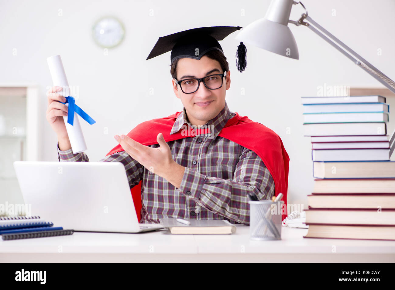 Super hero student wearing a mortarboard studying Stock Photo - Alamy