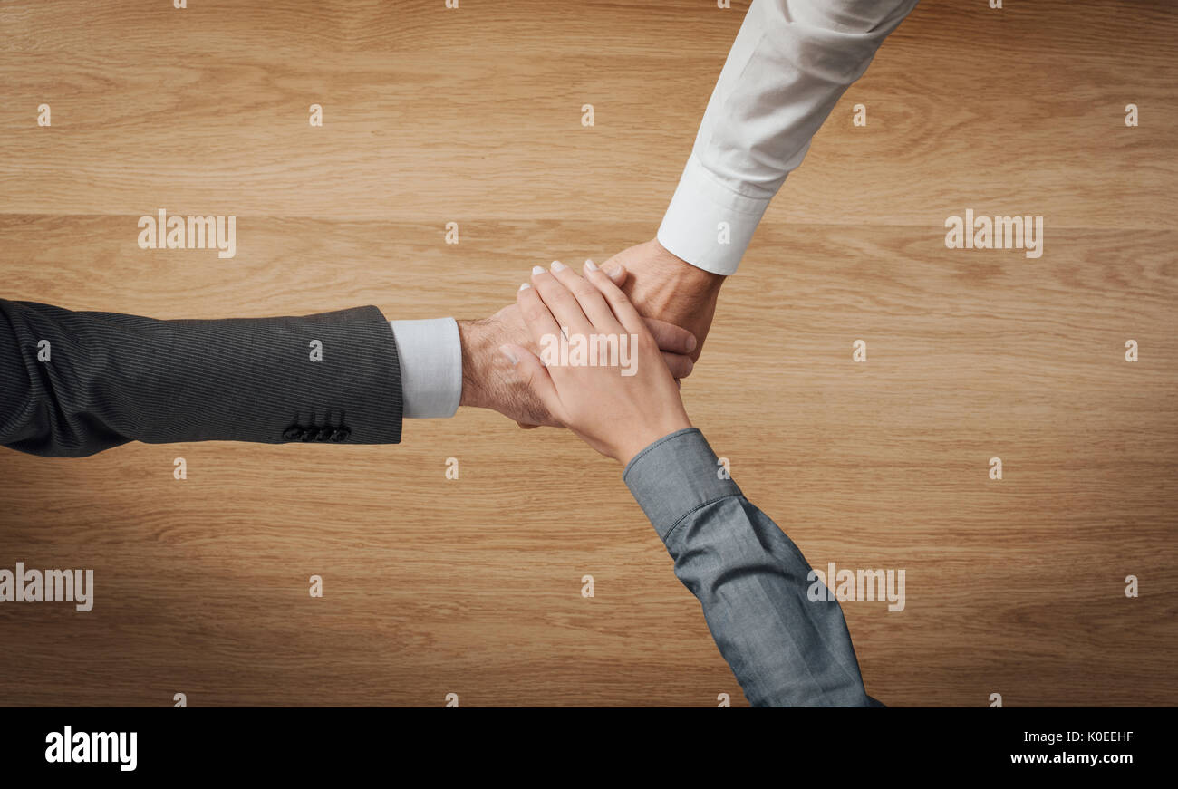 Business people stacking hands close up, wooden desktop on background ...