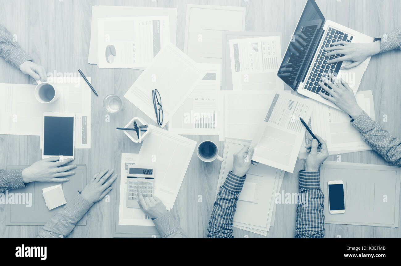 Business team working at office desk with paperwork, a laptop and a ...