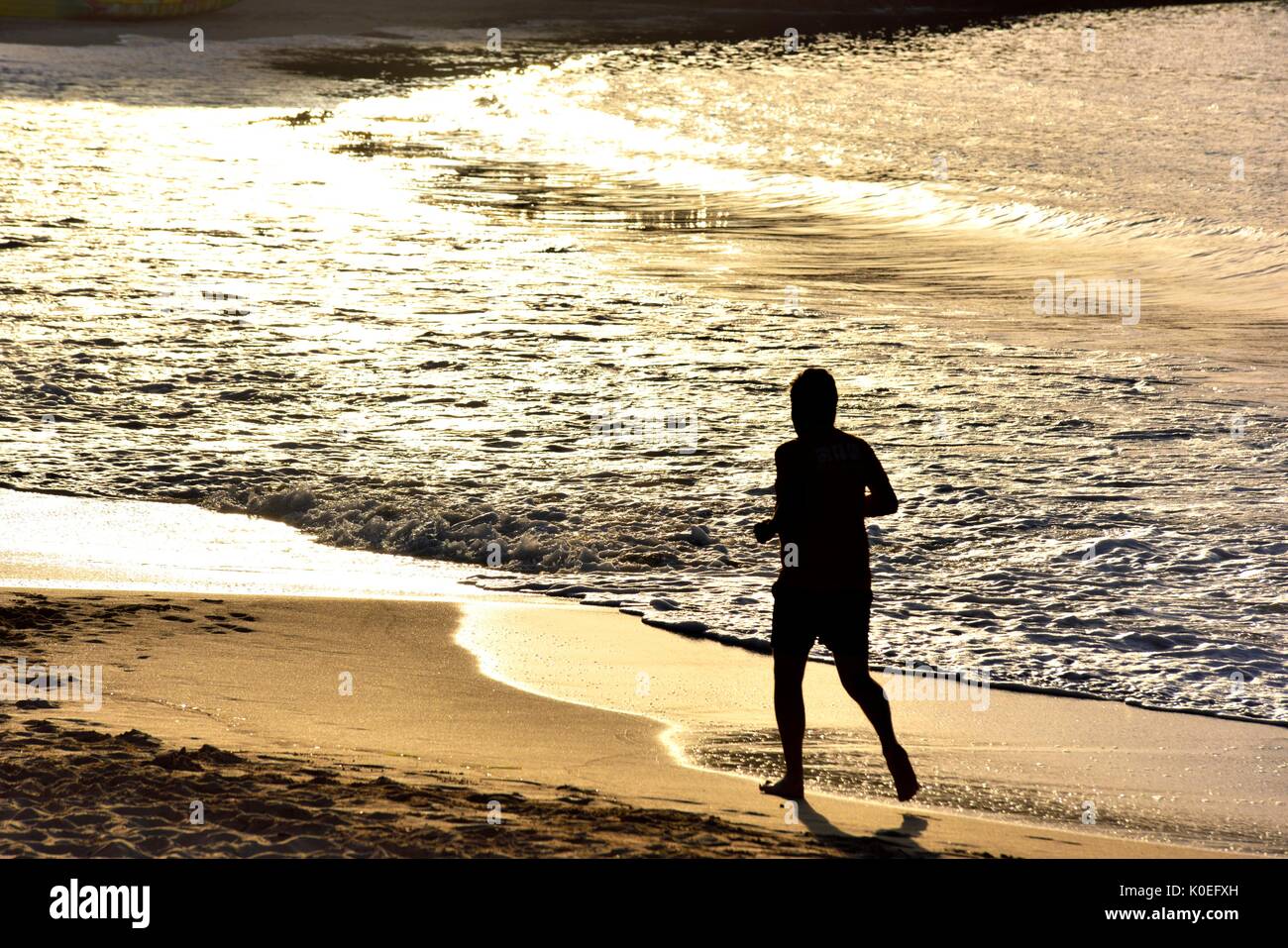 Man running along a beach at sunset menorca minorca Stock Photo - Alamy