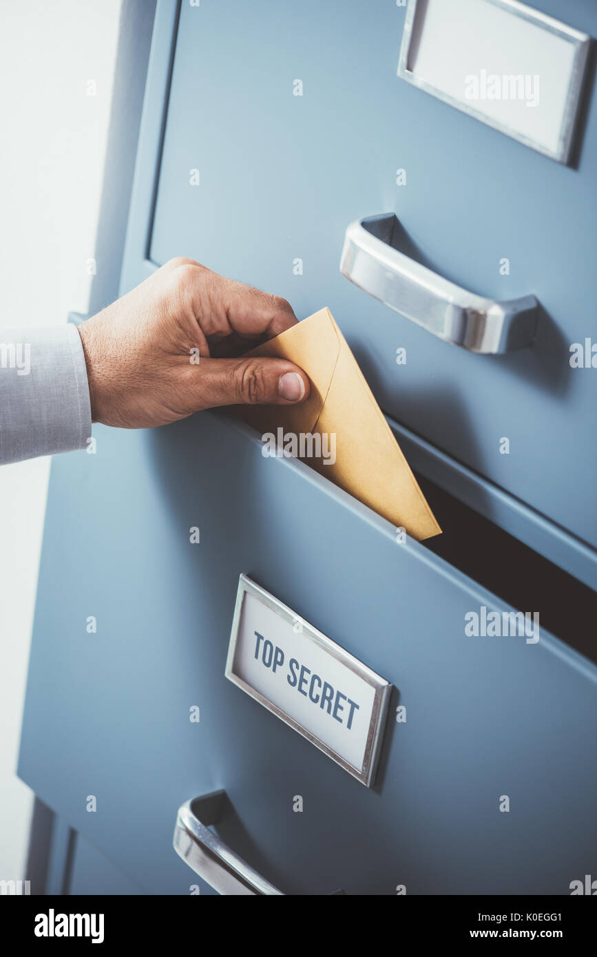 Businessman putting an envelope into a top secret classified drawer ...