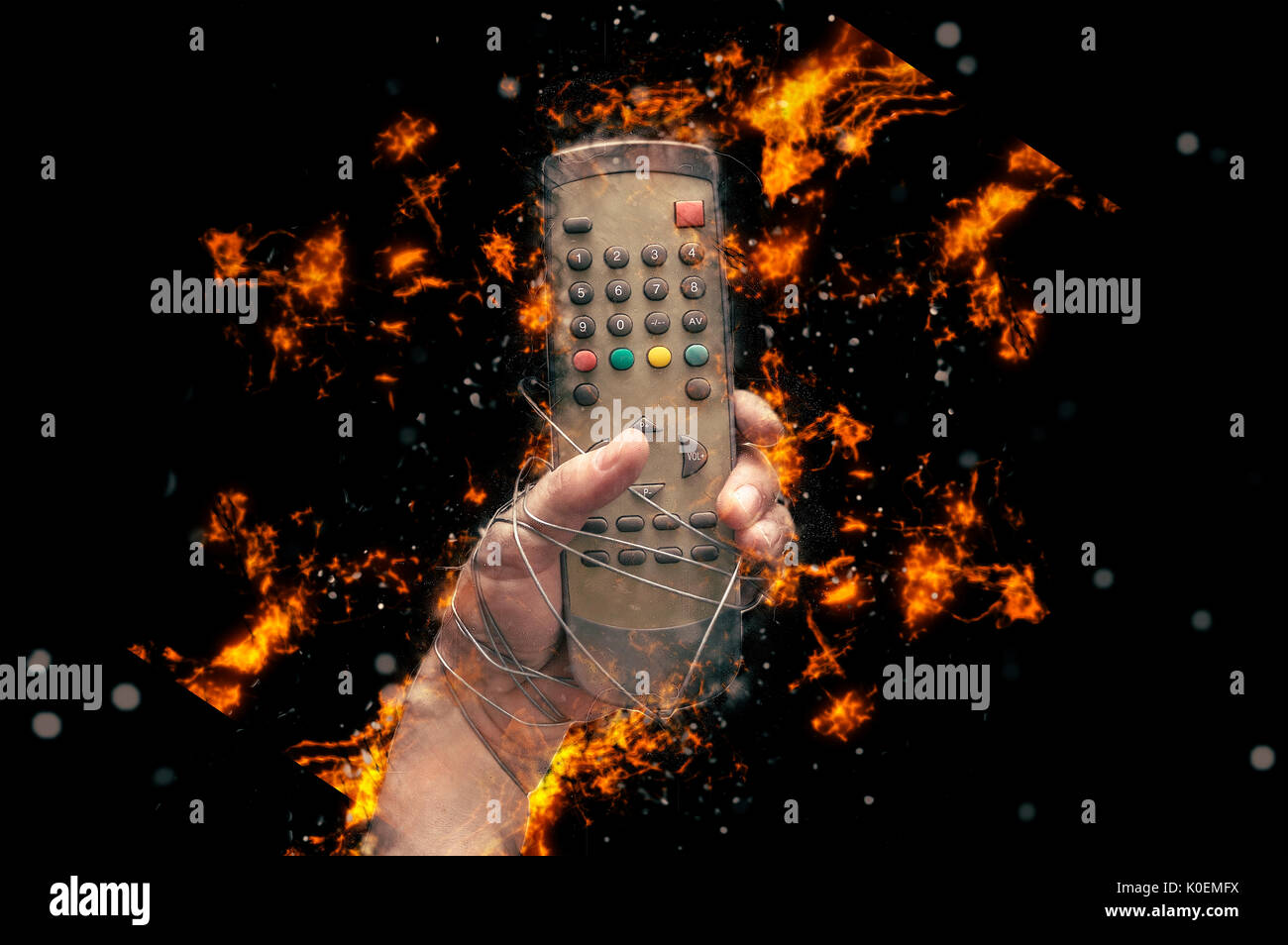 Hand with tv remote control tied with wire, depicting the idea of ...