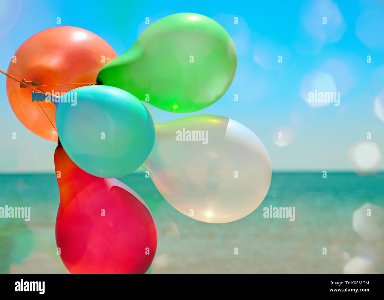 Multicolored balloons flying against the sea in the sun Stock Photo - Alamy