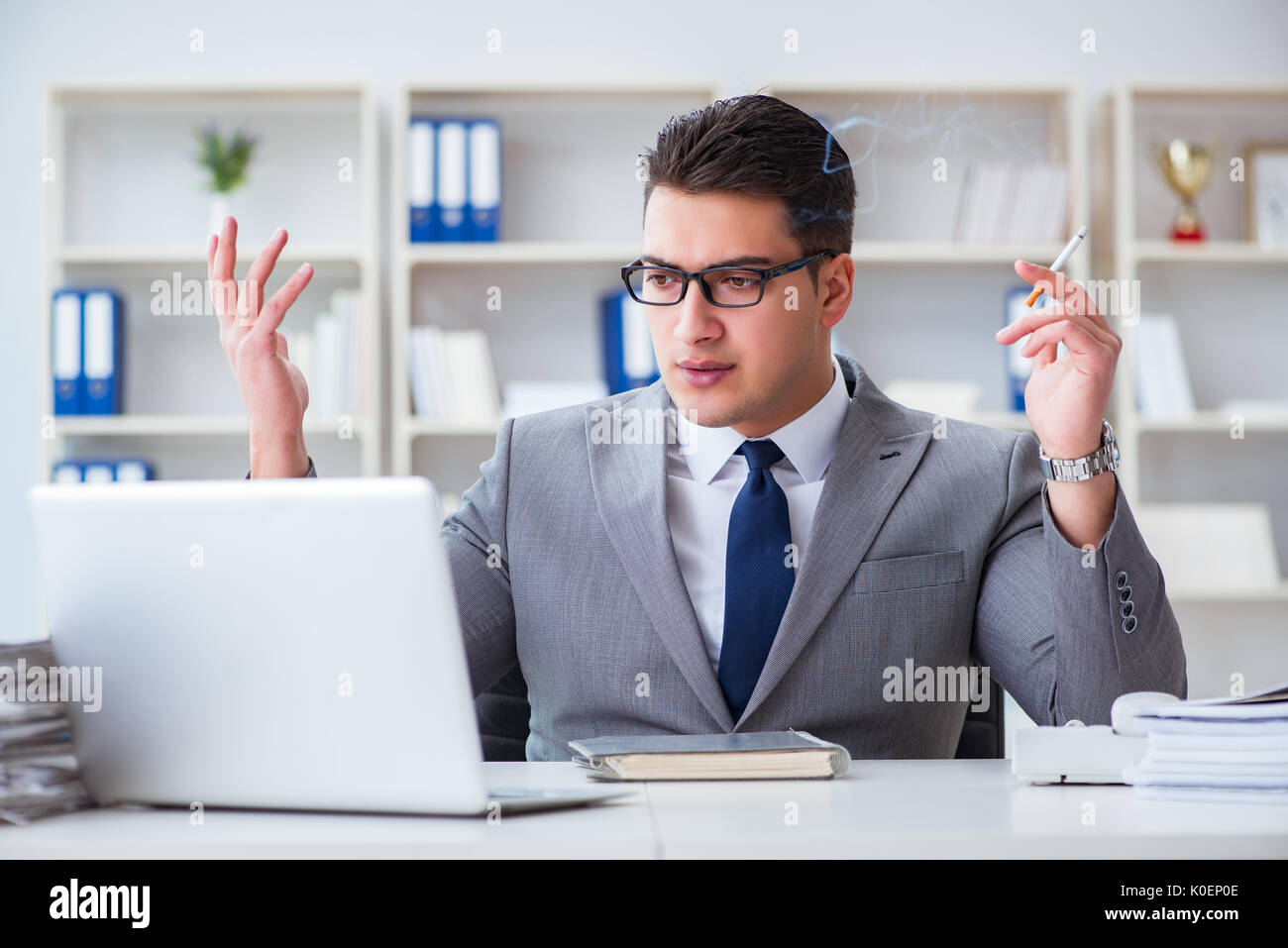 Businessman smoking in office at work Stock Photo - Alamy