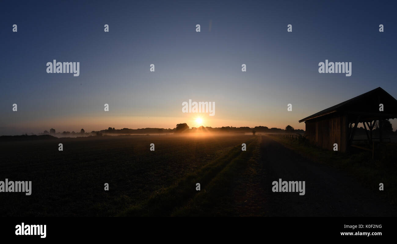 The sun rising over a field with a stable near Isernhagen, Germany, 23 ...