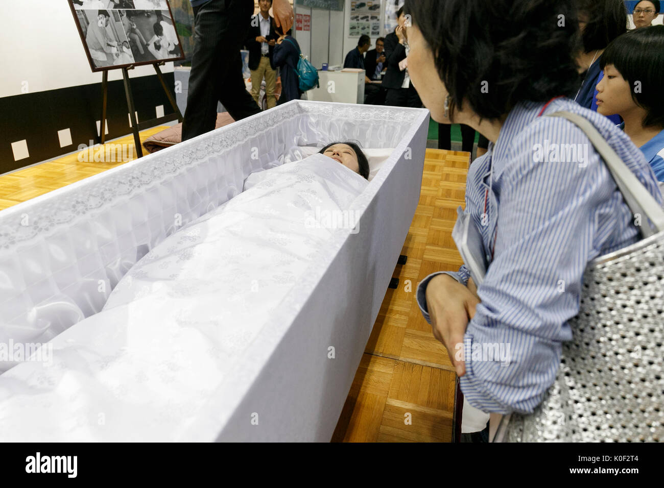 Visitors look at a member of staff inside a coffin after concluding a ...