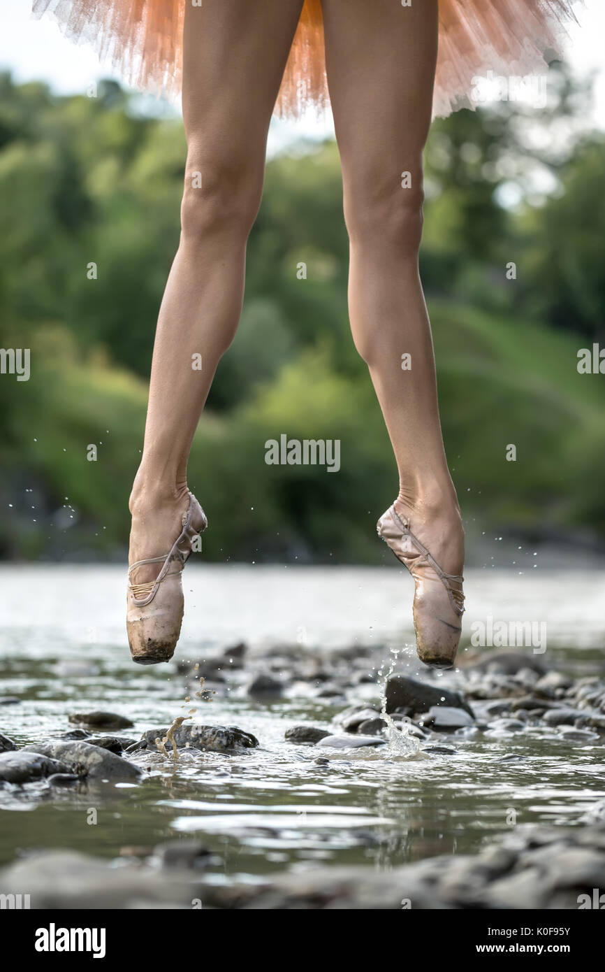 Dynamic ballerina jumping in the shallow river on the background of the ...