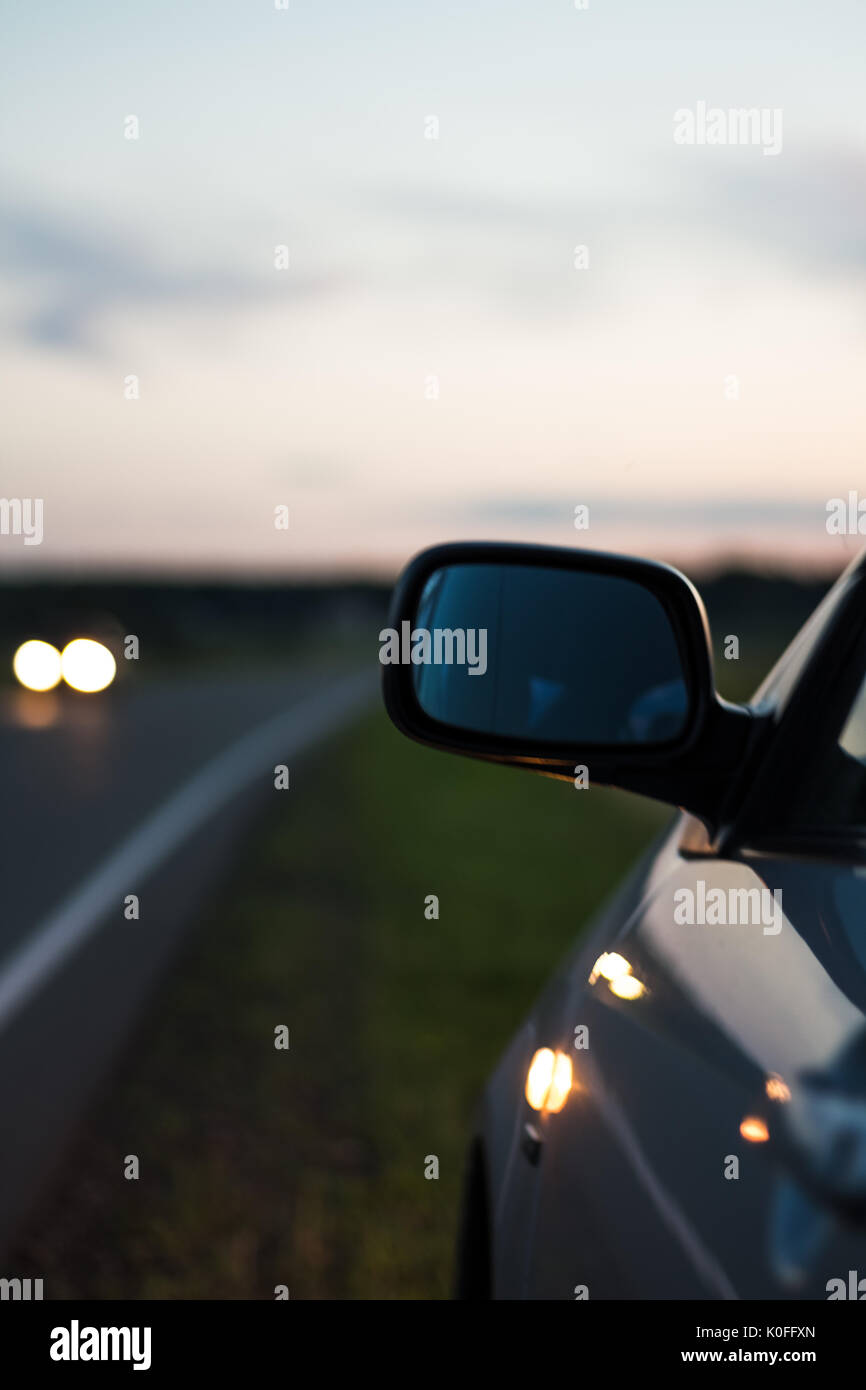 Car parked on the highway curb. Side mirror sticking out. Another car ...