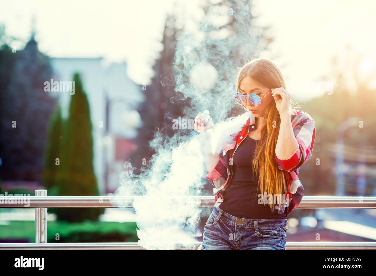 Young pretty hipster woman vaping and releases a cloud of vapor. The ...