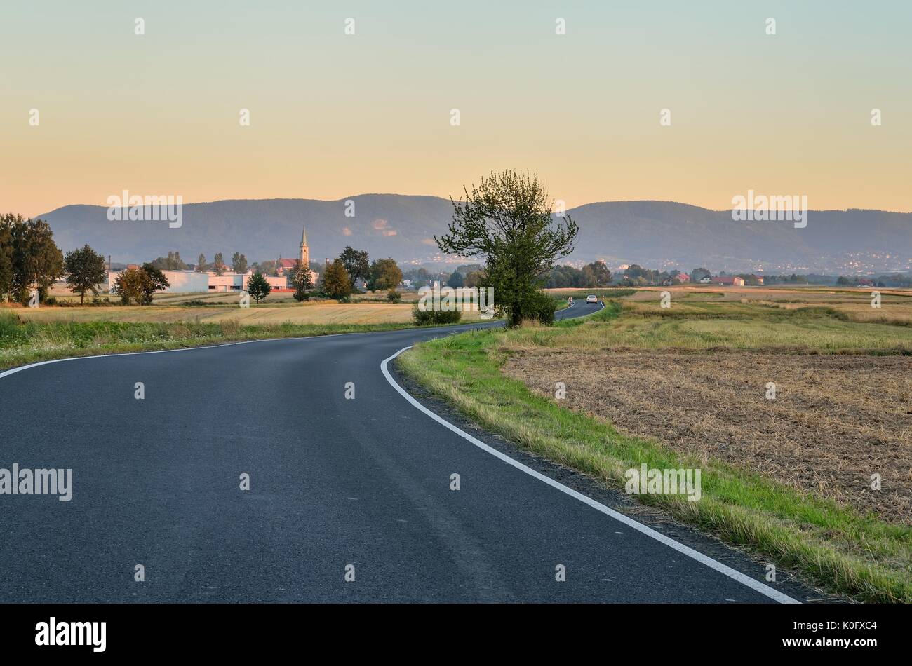 Summer rural landscape. Asphalt road with mountains and village in the ...