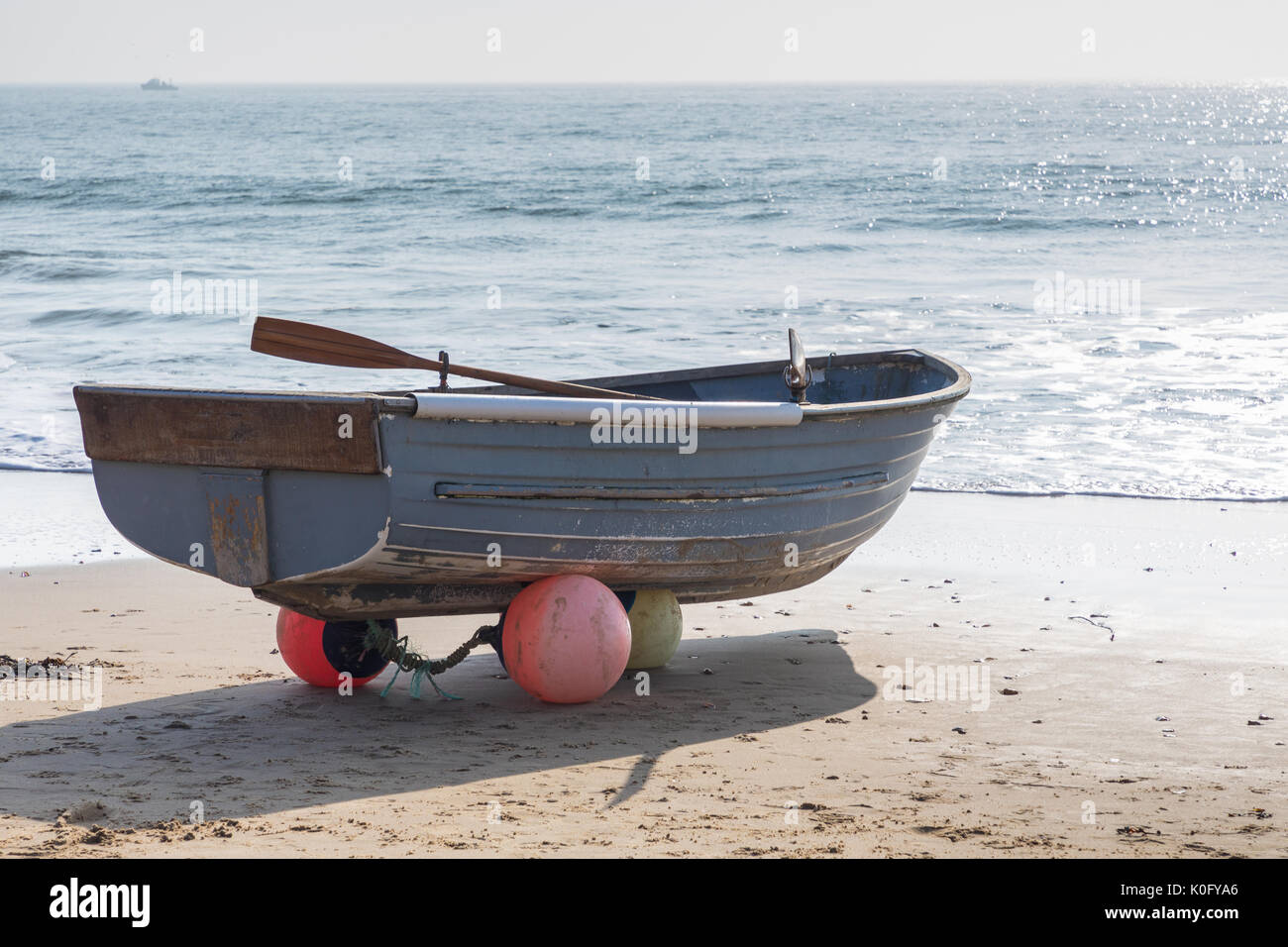 Fishing dinghy sitting on buoys on shoreline Stock Photo - Alamy