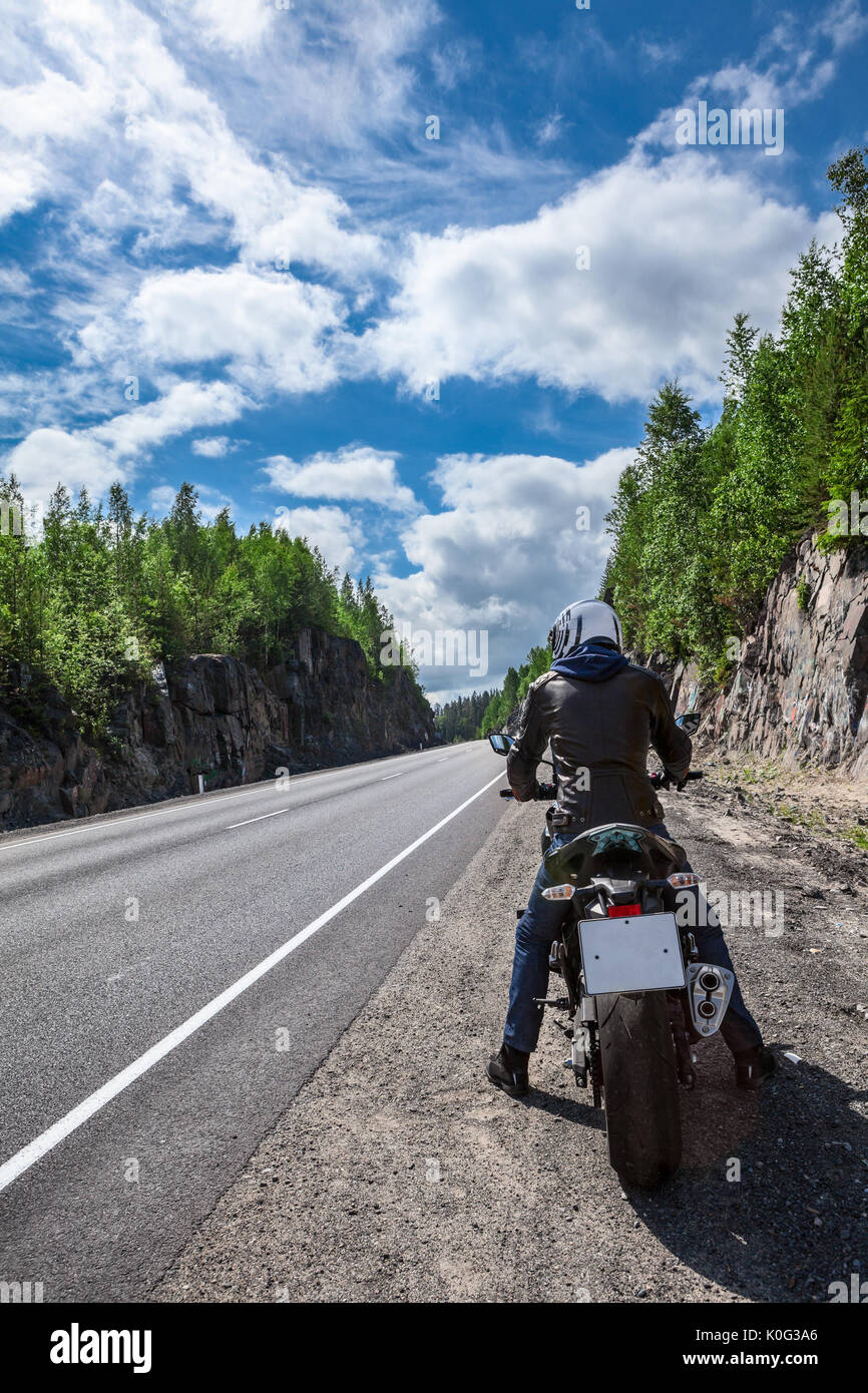 Motorcycle driver is ready to start driving on the asphalt road ...